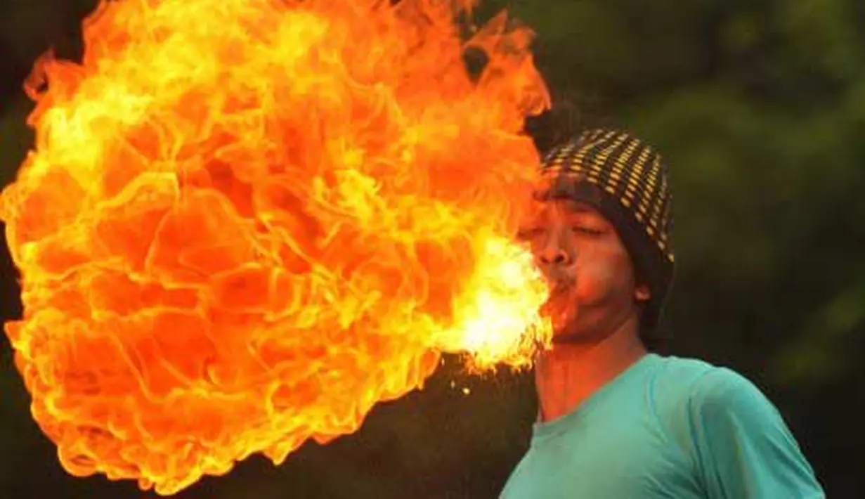 Seorang pemain kuda lumping menyemburkan api dari mulutnya saat ...