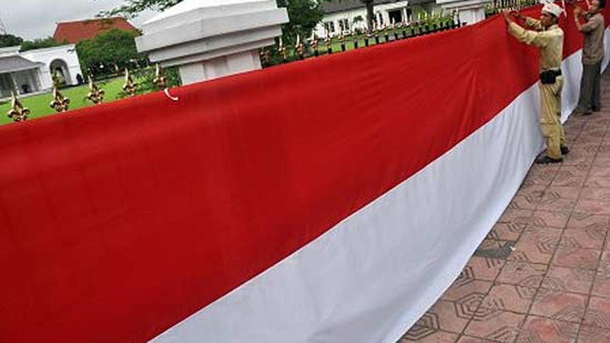 Sejumlah petugas memasang bendera merah putih sepanjang 66 meter saat ...